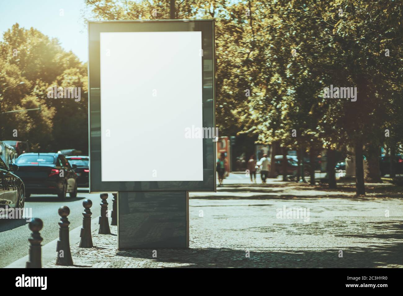 Blank white advert billboard template on paving stone near a busy road ...