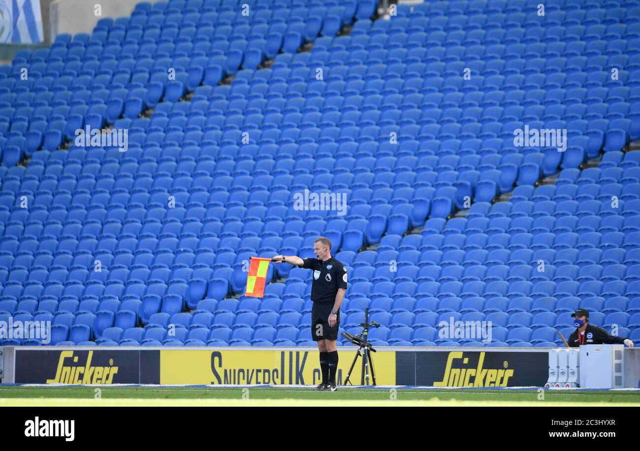 The assistant referee raises his flag with a sea of empty seats behind ...