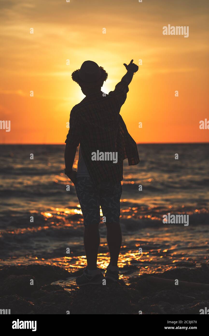 Silhouette man hand pointing out in sky at sunset. Travel beach ...
