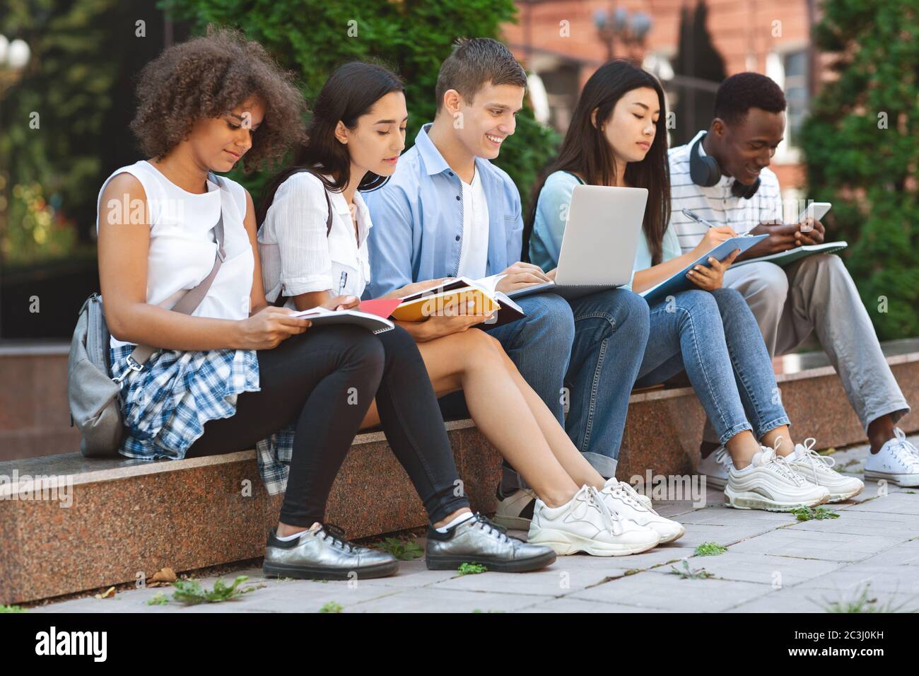 Group of multiethnic students studying in the courtyard of university ...