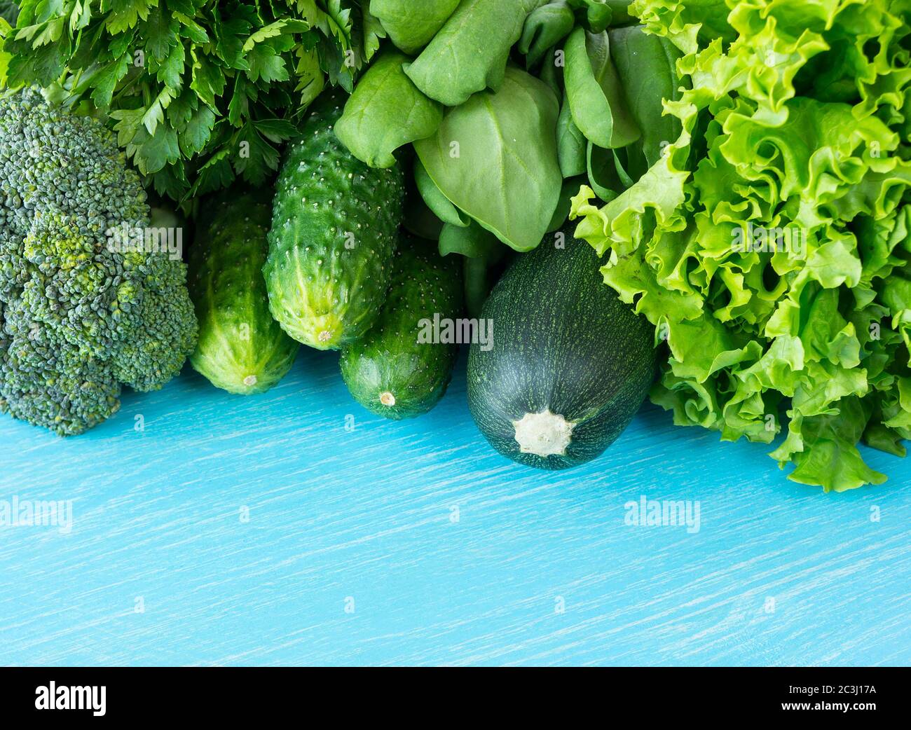 Green vegetables on a blue wooden background. Parsley, spinach ...
