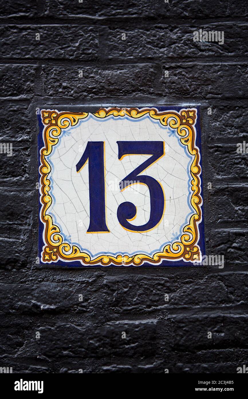 Decorative delftware tile with the number 13, on a black painted wall ...