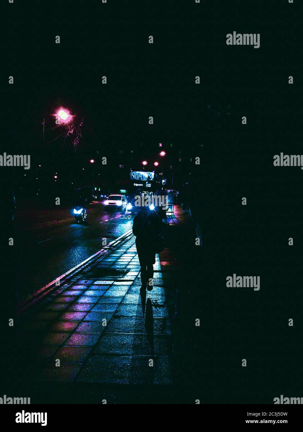 Vertical shot of a human silhouette walking along an urban sidewalk ...