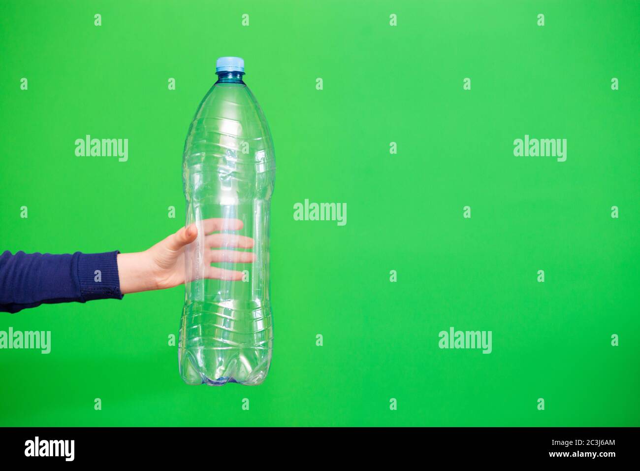 Child hand hold plastic bottle isolated on green background. Ecology ...