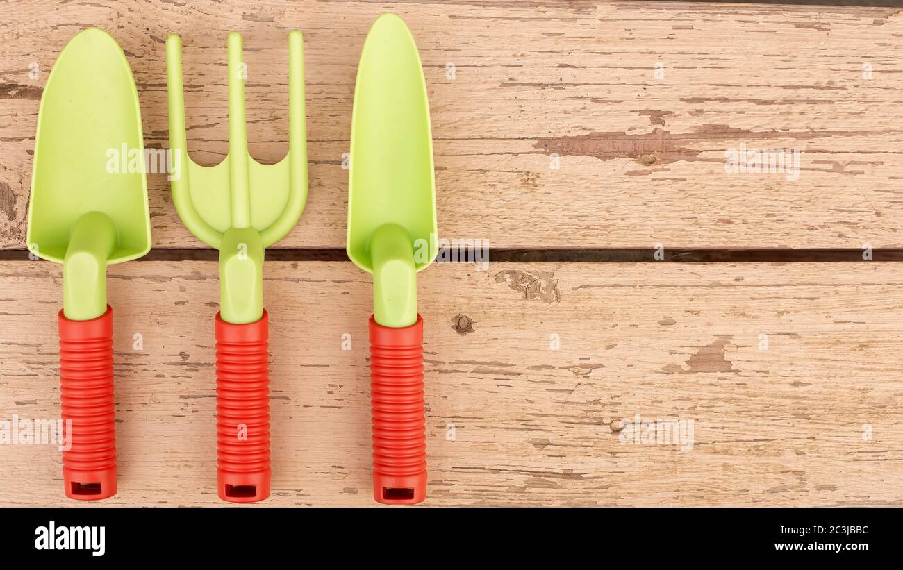 Light green garden tools with orange handles lie on painted boards ...