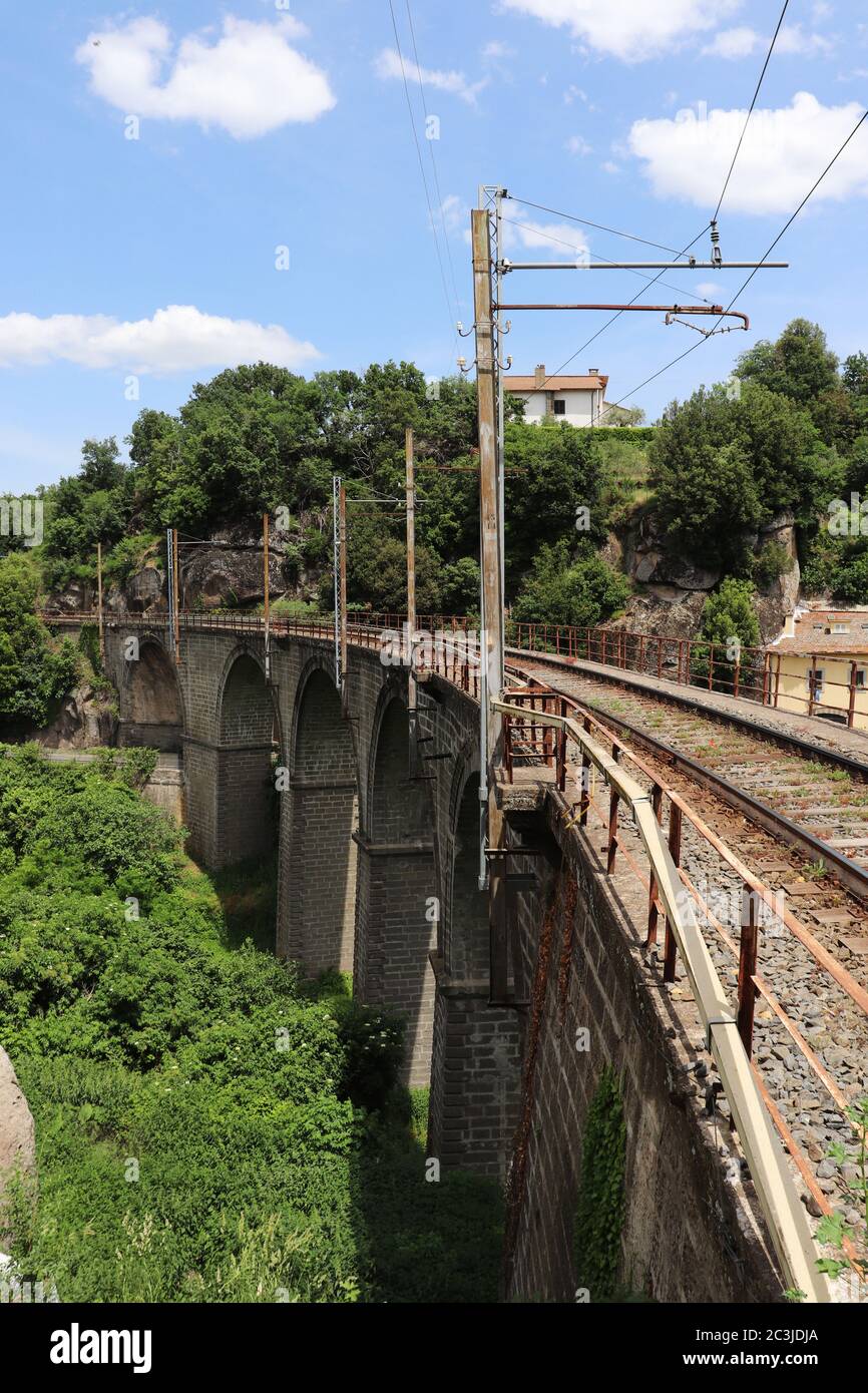 The railroad tracks pass over a stone bridge through a landscape full ...