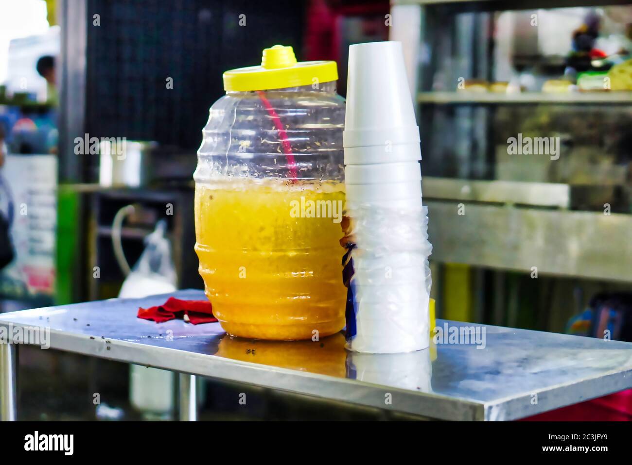 Yellow juice on a big bottle with cups Stock Photo - Alamy