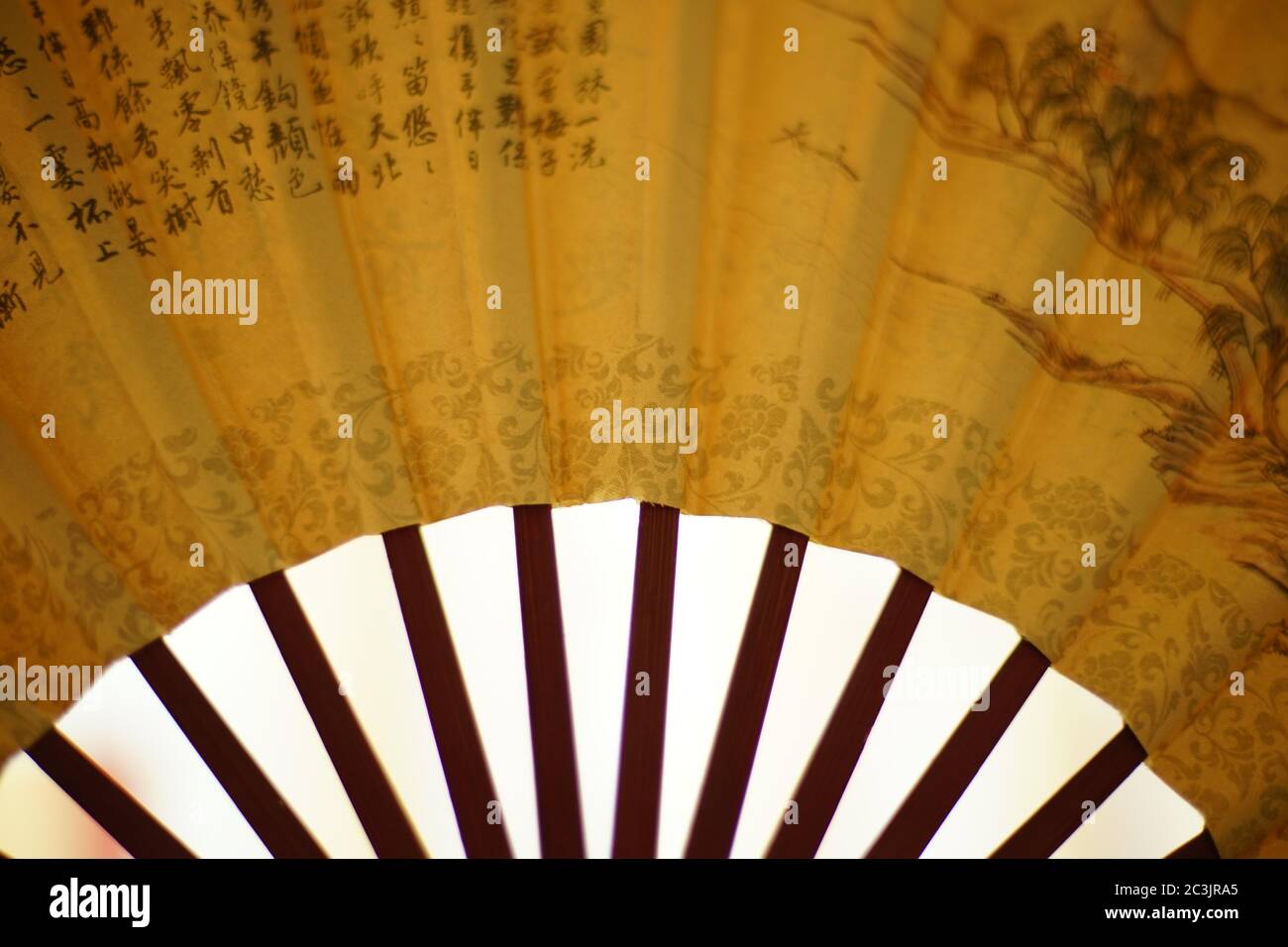 yellow fan with brown chinese characters on it, white background ...