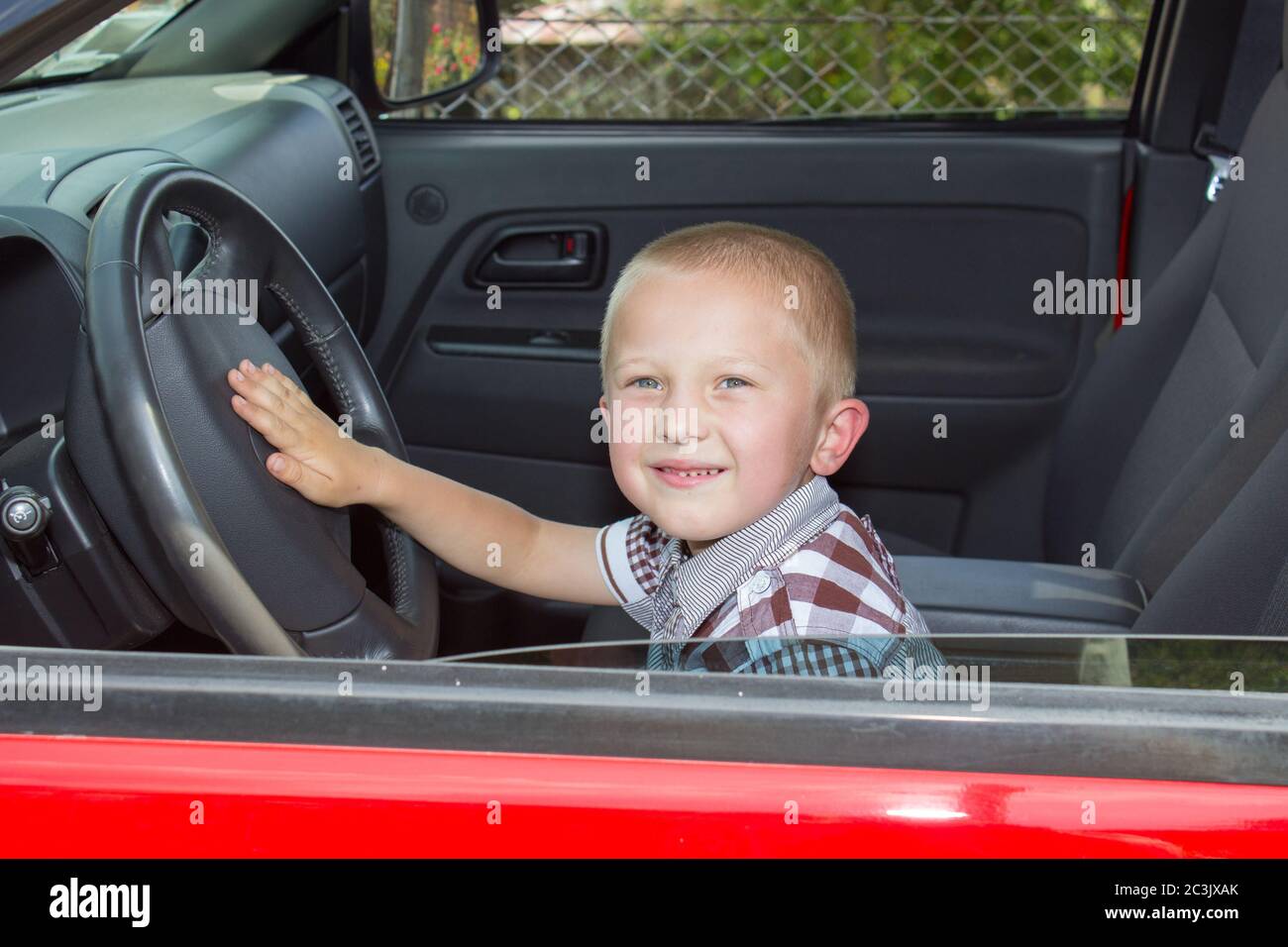 baby boy sitting at the wheel of a car. smiling baby driving a car ...