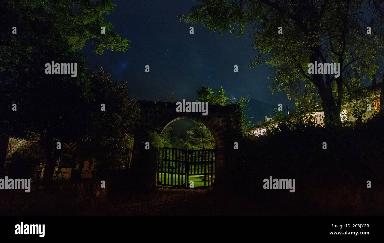 Night view of an old stone gate in a country house surrounded by trees ...