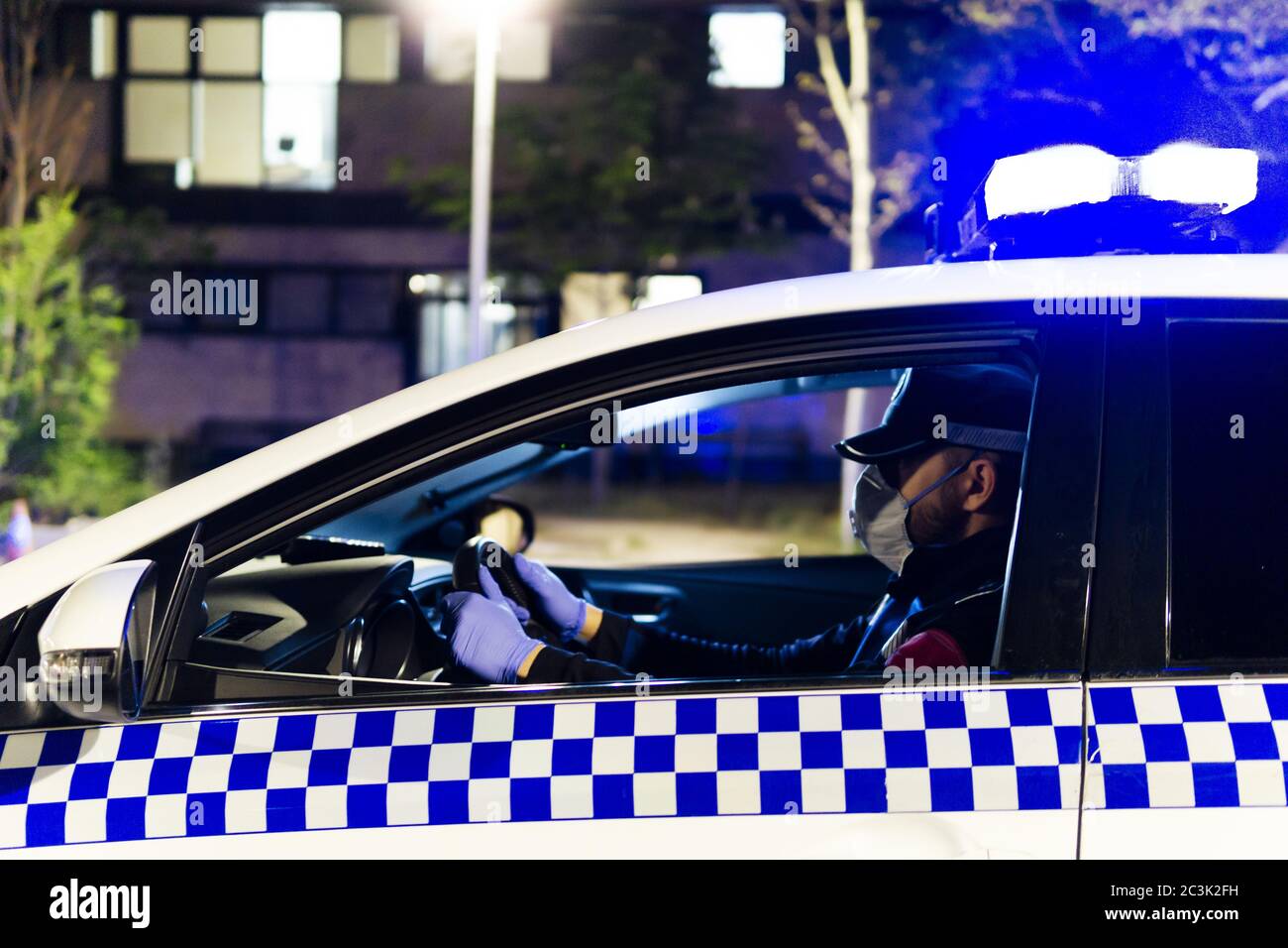 Closeup shot of a policeman with medical face mask driving police car ...