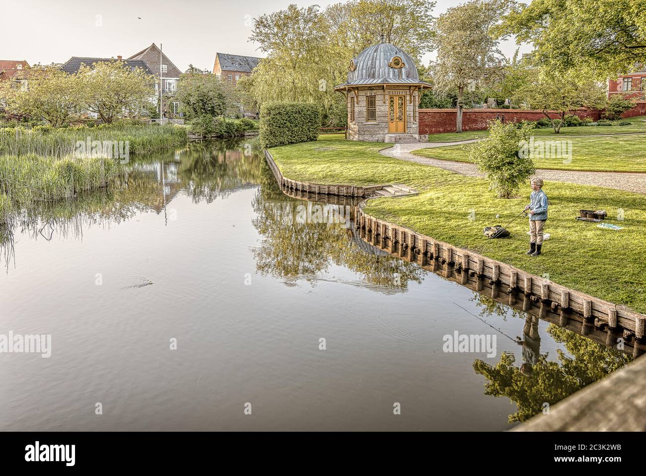 boy fishing in the calm water of Ribe river, Ribe, Denmark, May 29 ...