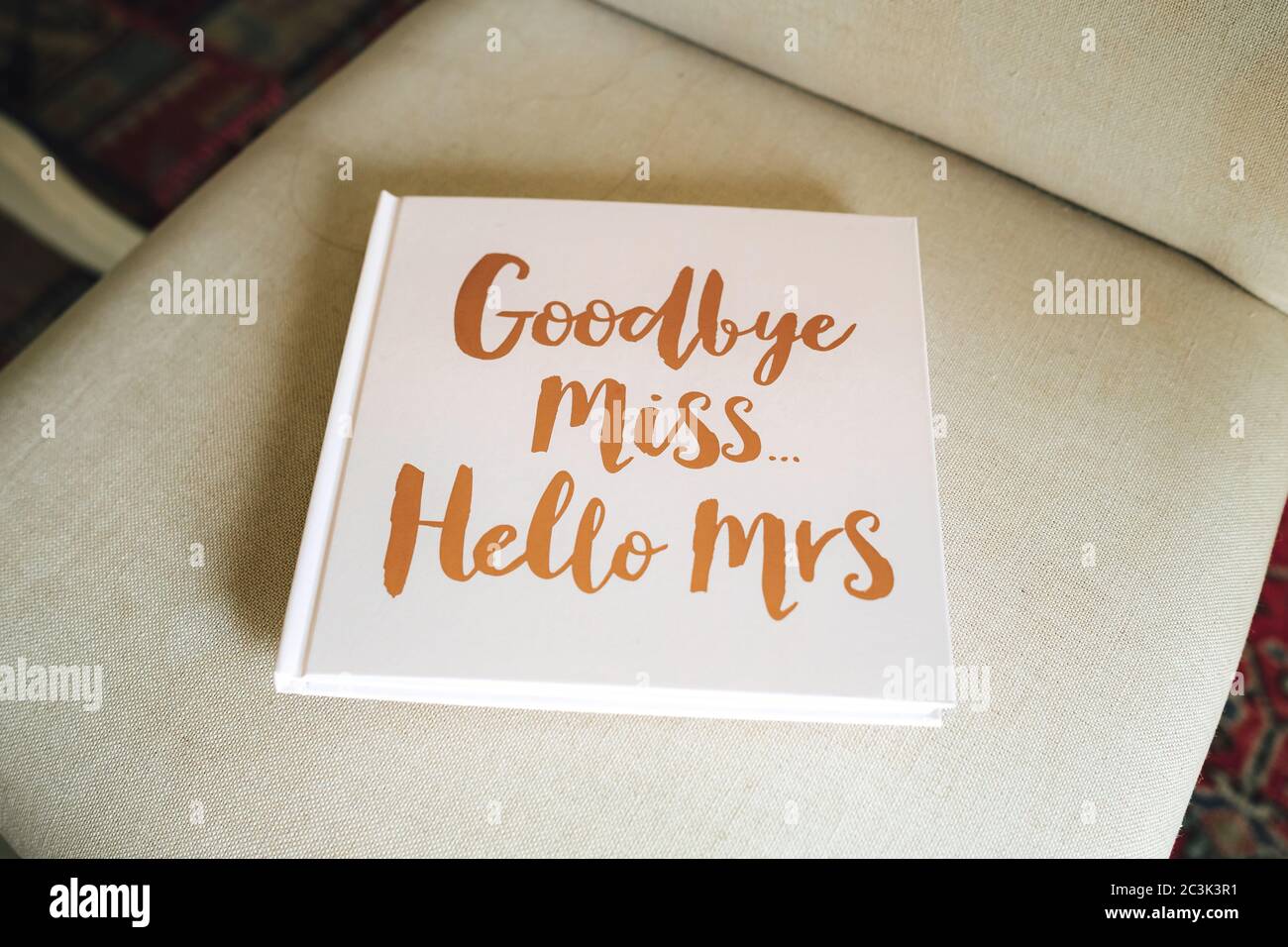 Closed white book laying on white upholstered chair. Text on book cover ...