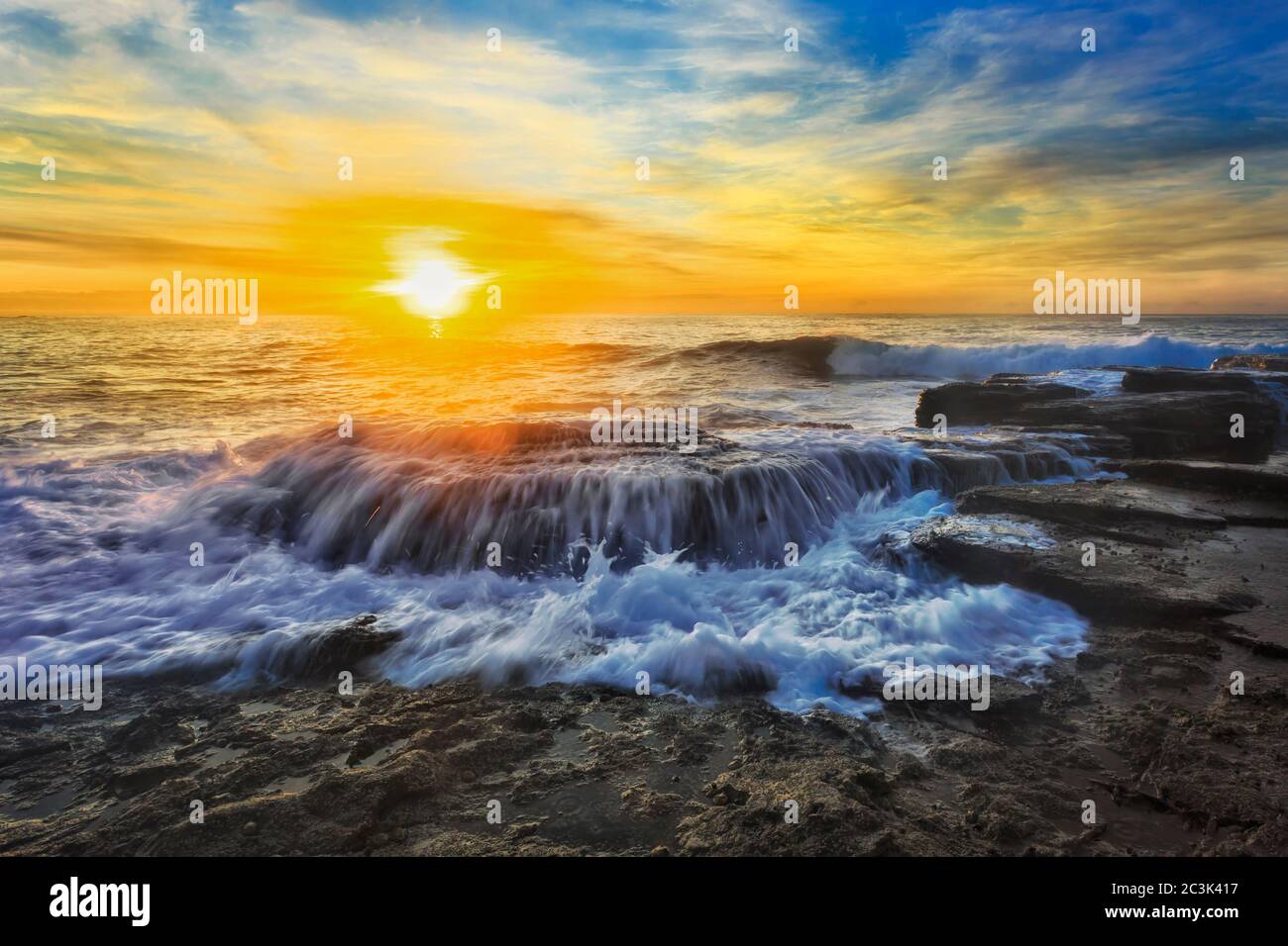 Pacific ocean wave flows over sandstone rock off Narrabeen headland on ...