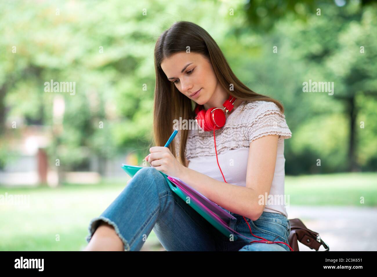 Young woman student studying outdoor in front of her school college ...