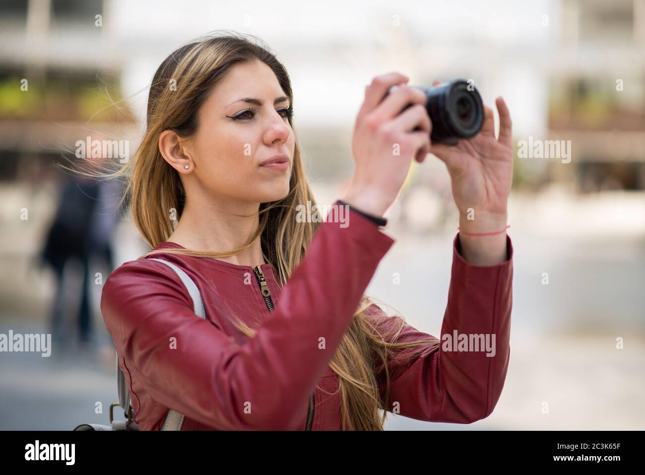 Woman using her mirrorless camera in a city Stock Photo - Alamy