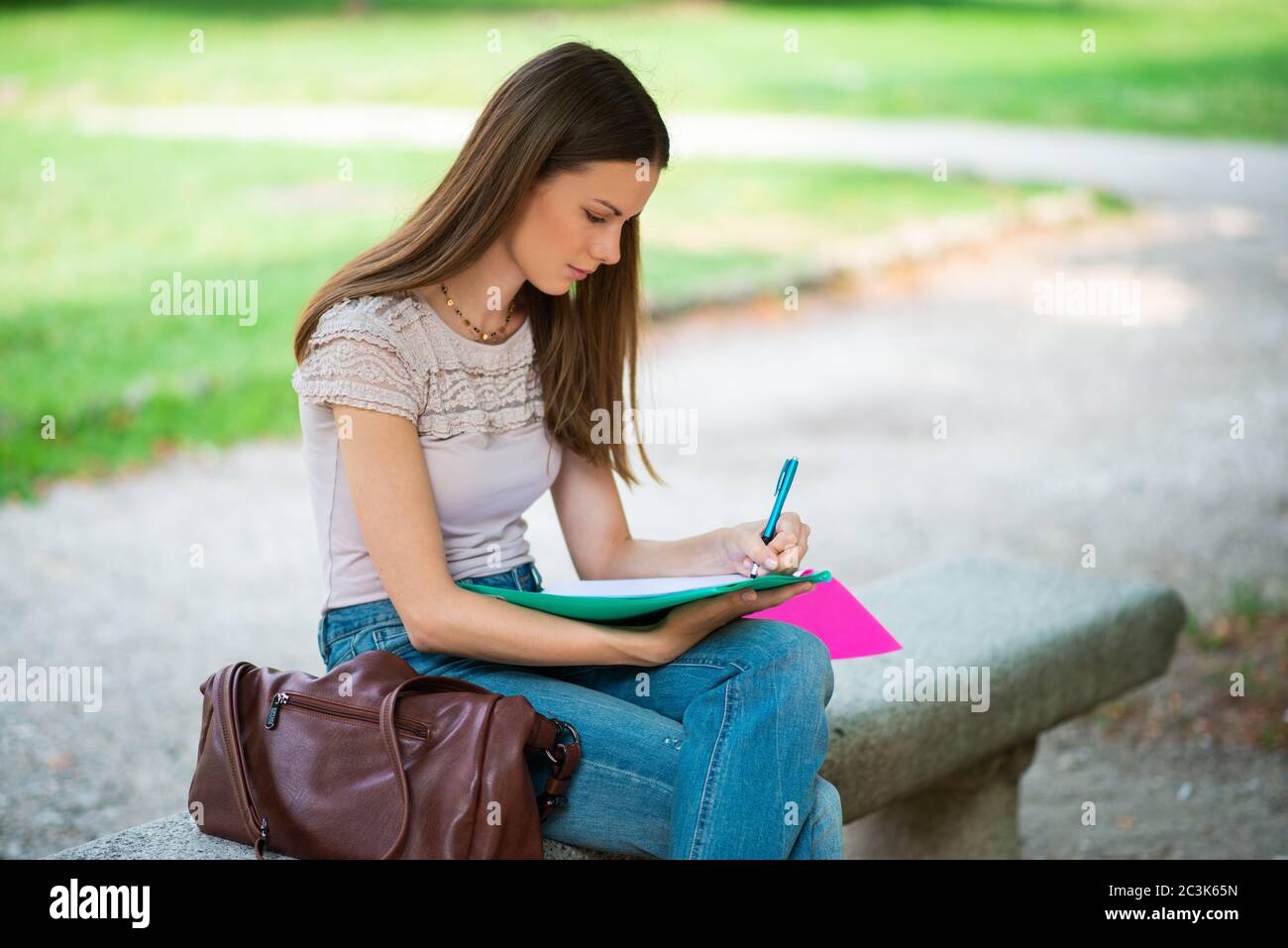 Young woman student studying outdoor in front of her school college ...