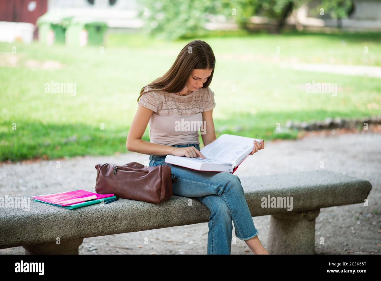 Young woman student studying outdoor in front of her school college ...