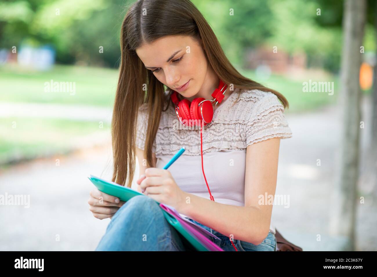 Young woman student studying outdoor in front of her school college ...