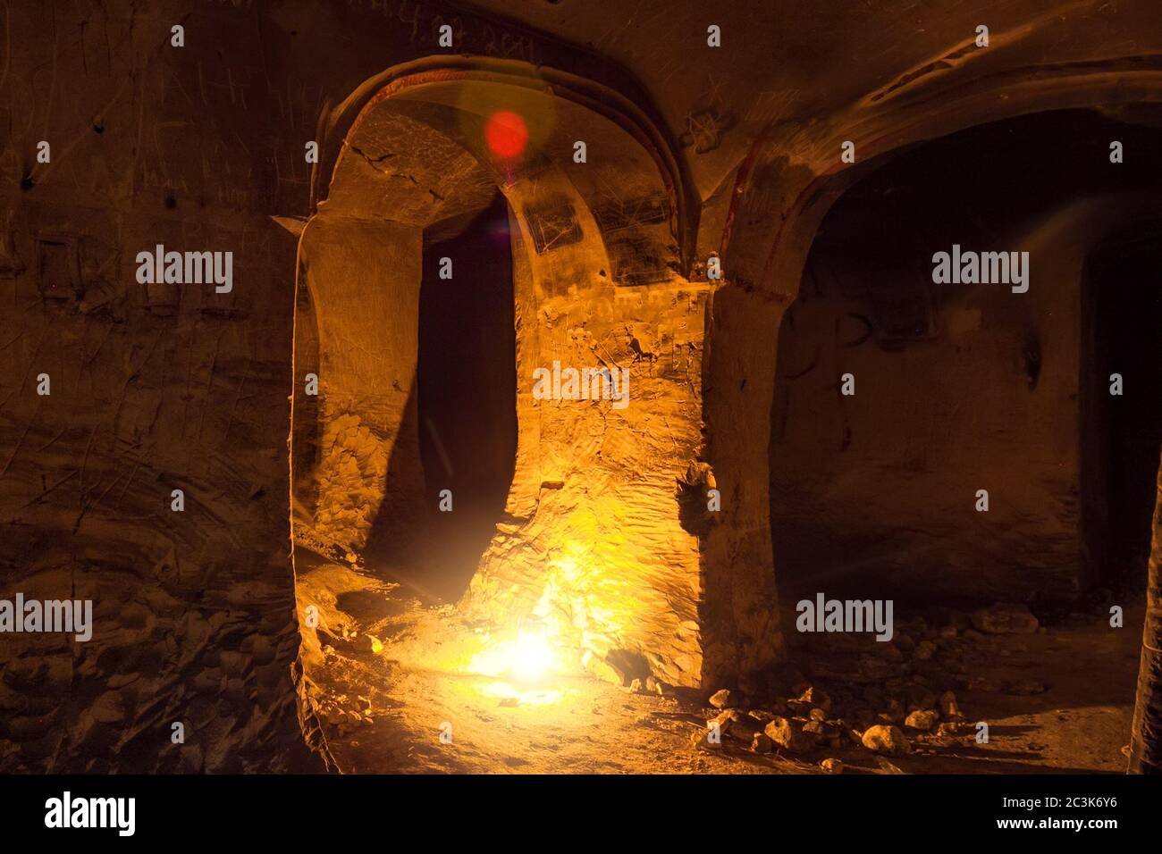 Dark abandoned underground chalky cave temple illuminated by candles ...
