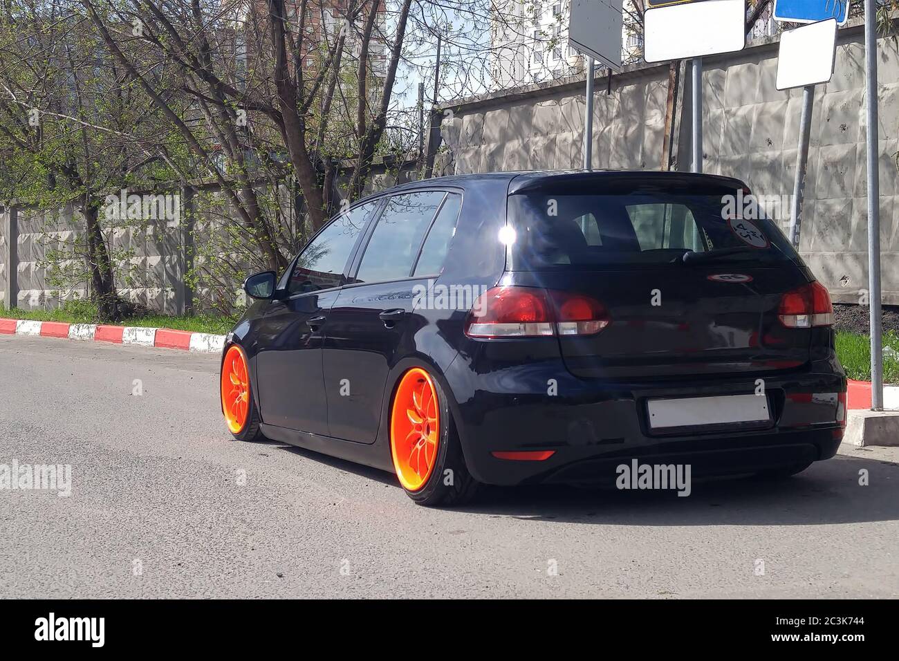Black hatchback with orange wide wheels tuned by air suspencion parked ...