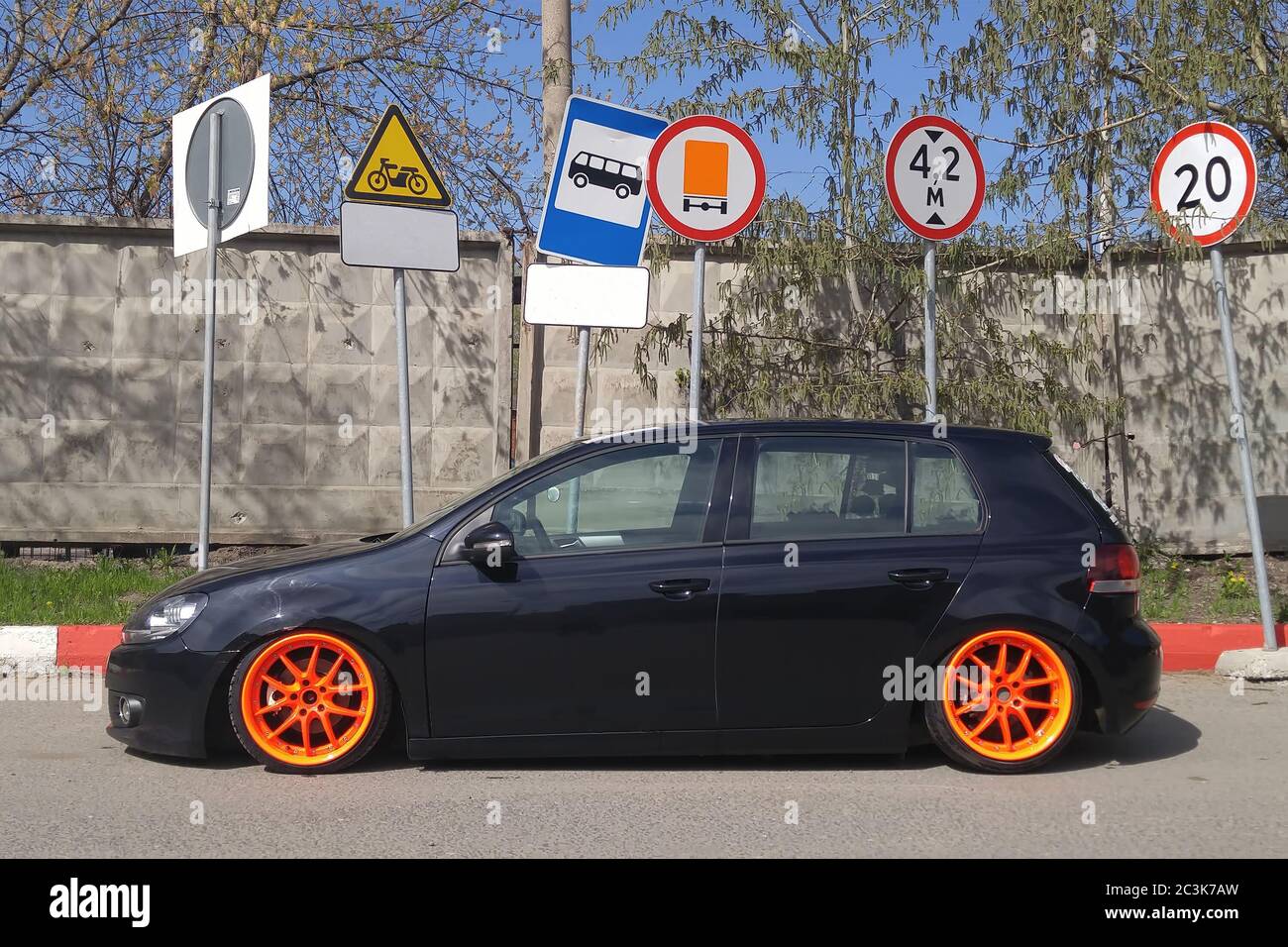 Black hatchback with orange wide wheels tuned by air suspencion parked ...