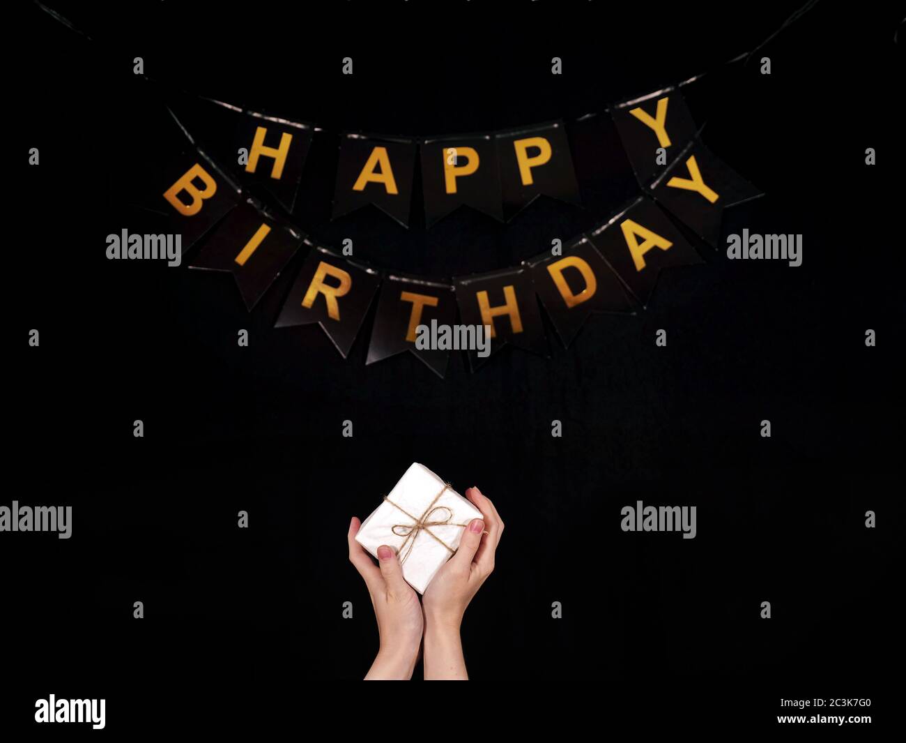 Faceless person holding a white gift in his hands on a black isolated ...