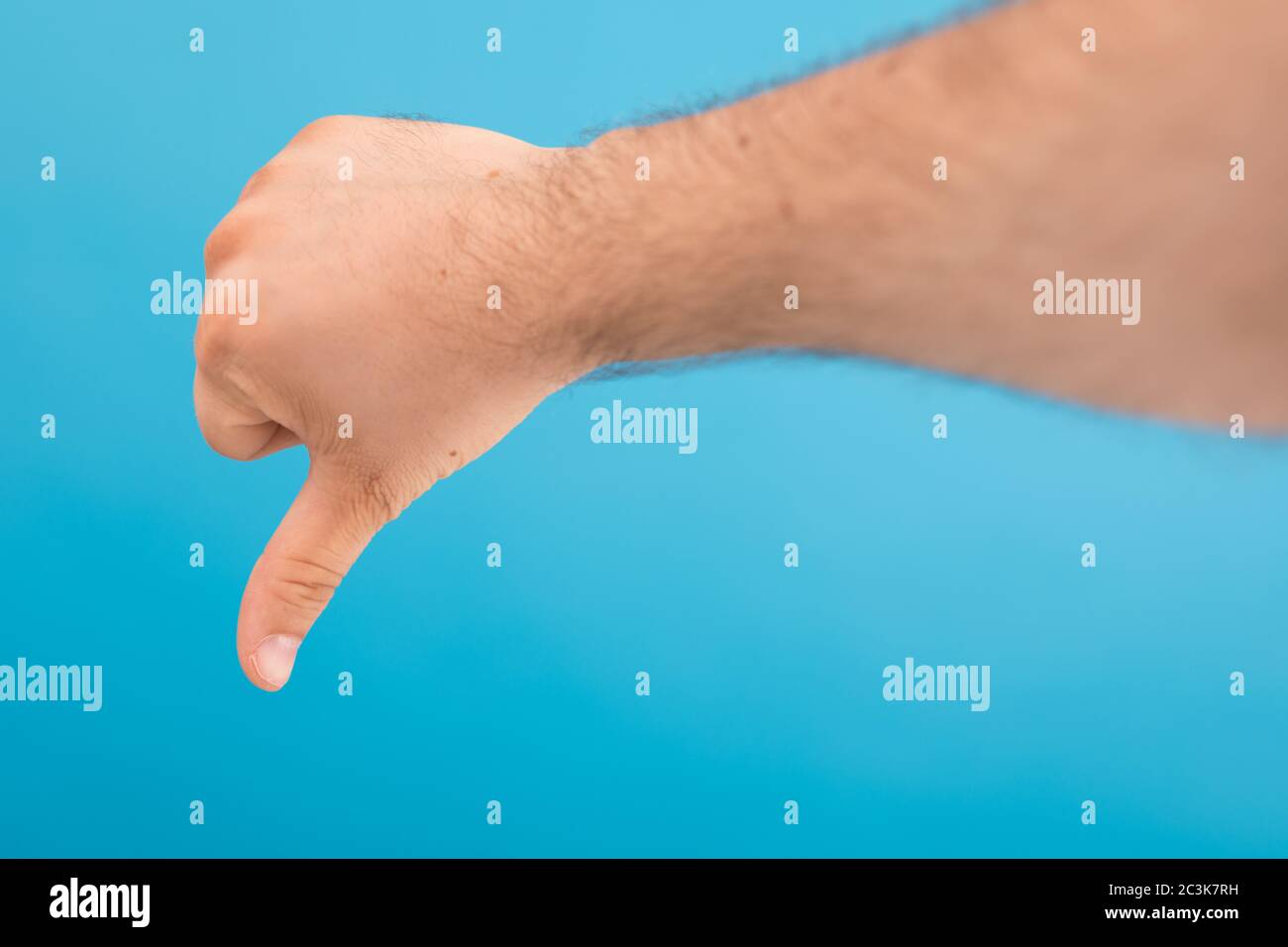 Closeup of a person doing the thumbs-down gesture under the lights ...