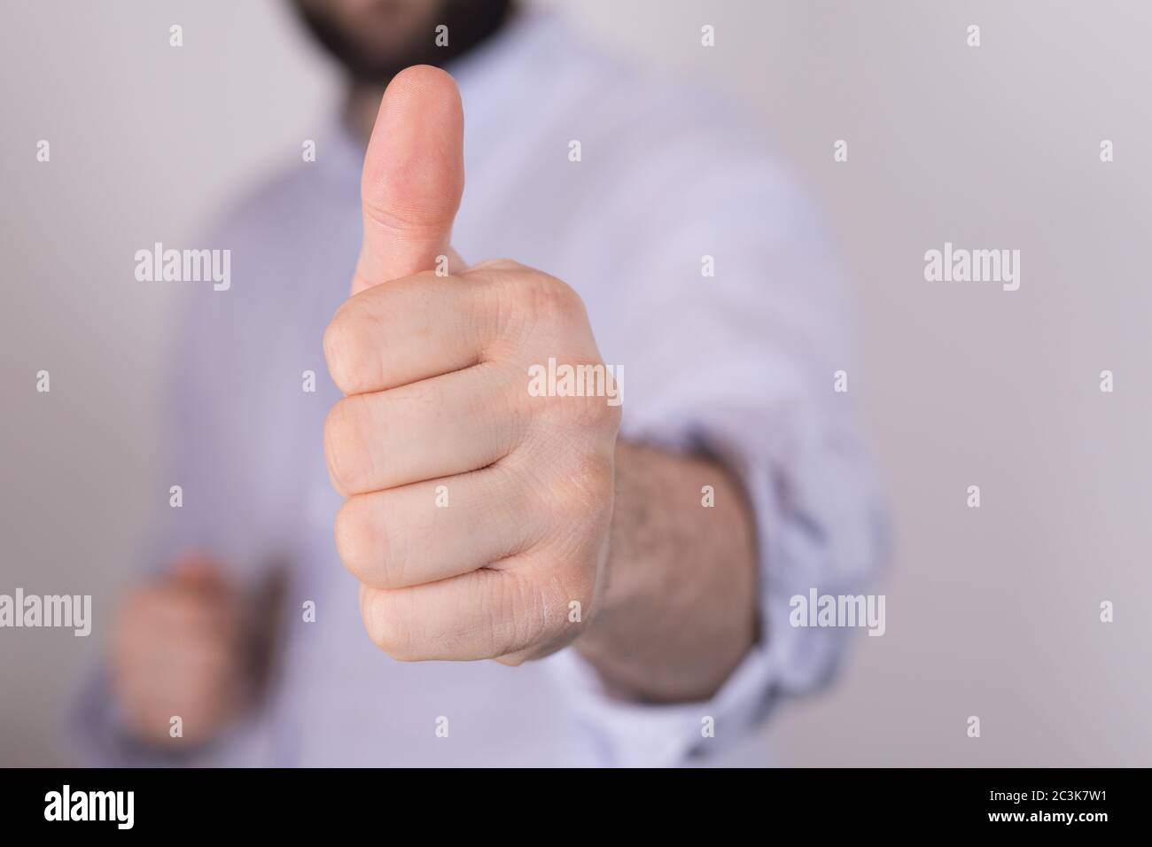 Closeup of a person doing the thumbs-up gesture under the lights on a ...