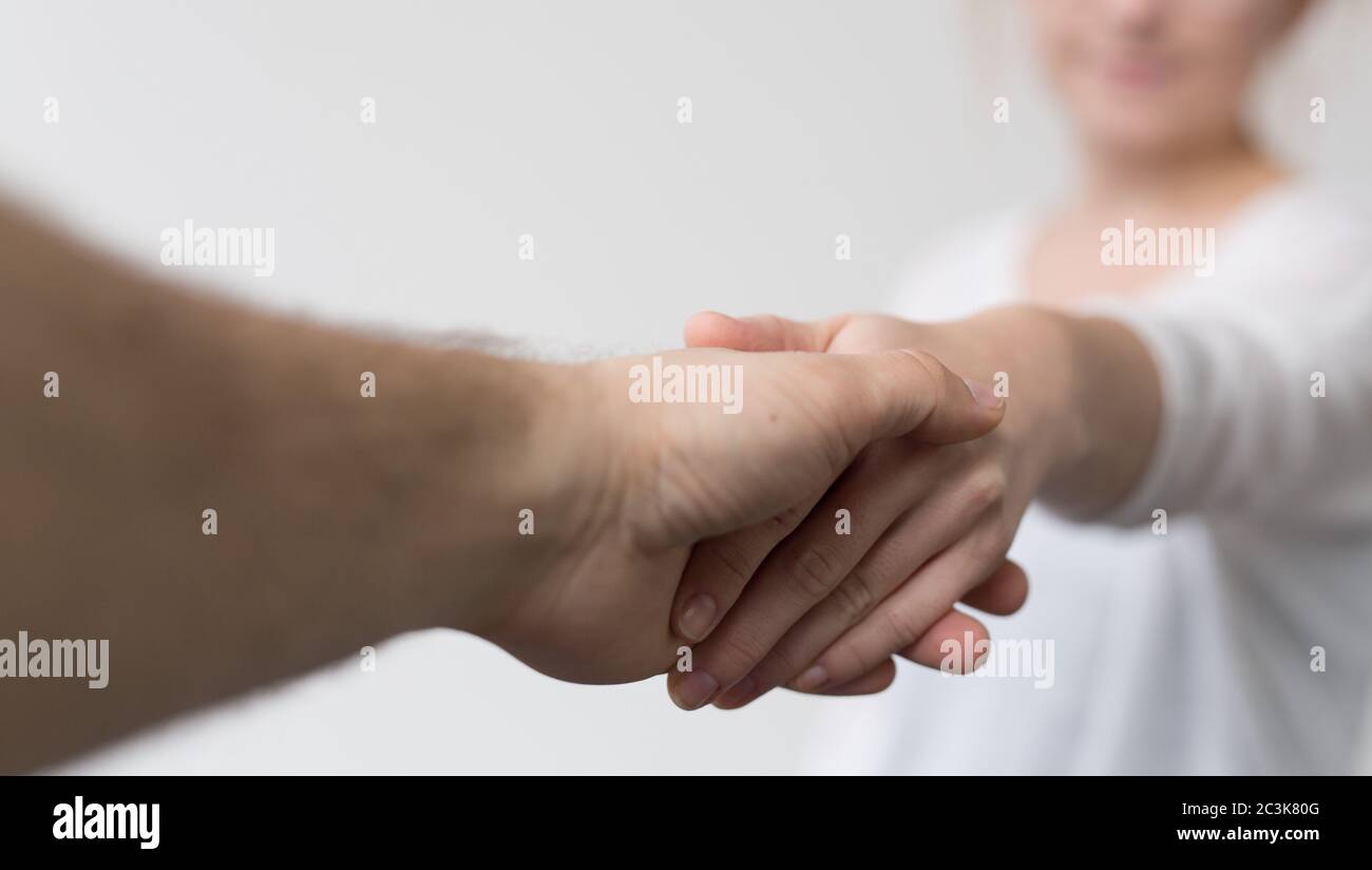 Closeup of people shaking hands under the lights on a blurry background ...