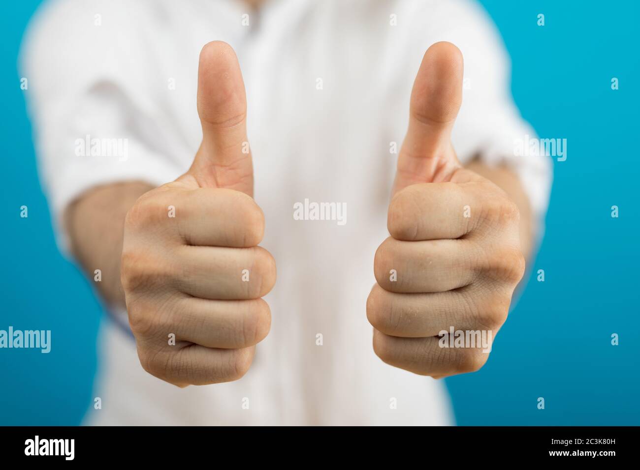 Closeup of a person doing the thumbs-up gesture under the lights on a ...