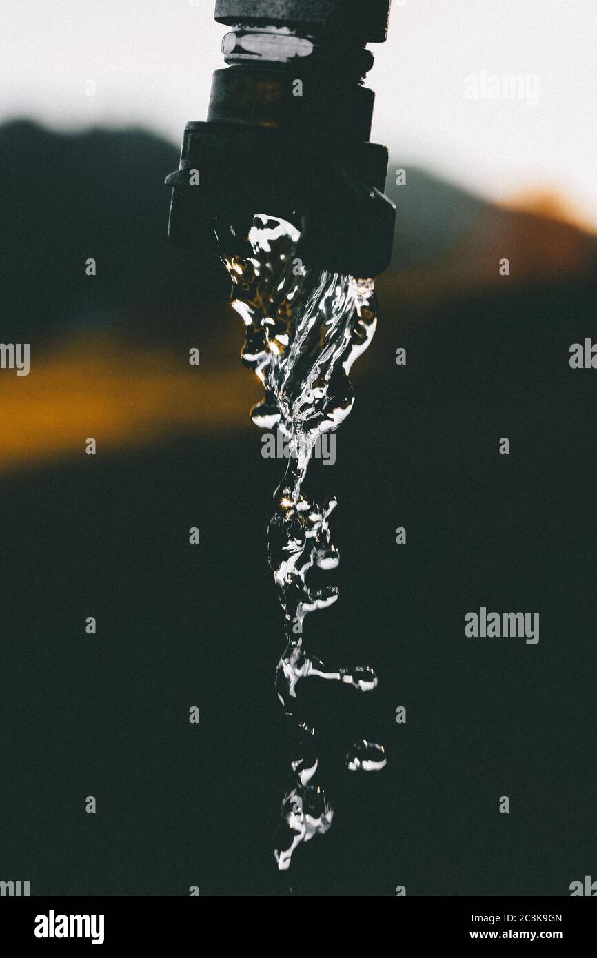 Vertical selective focus shot of the water dripping from a faucet with ...