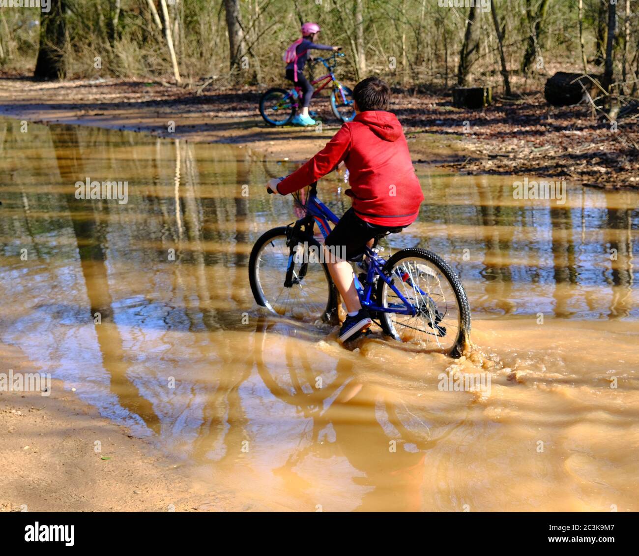 Boy Riding Through Mud Puddle Stock Photo - Alamy