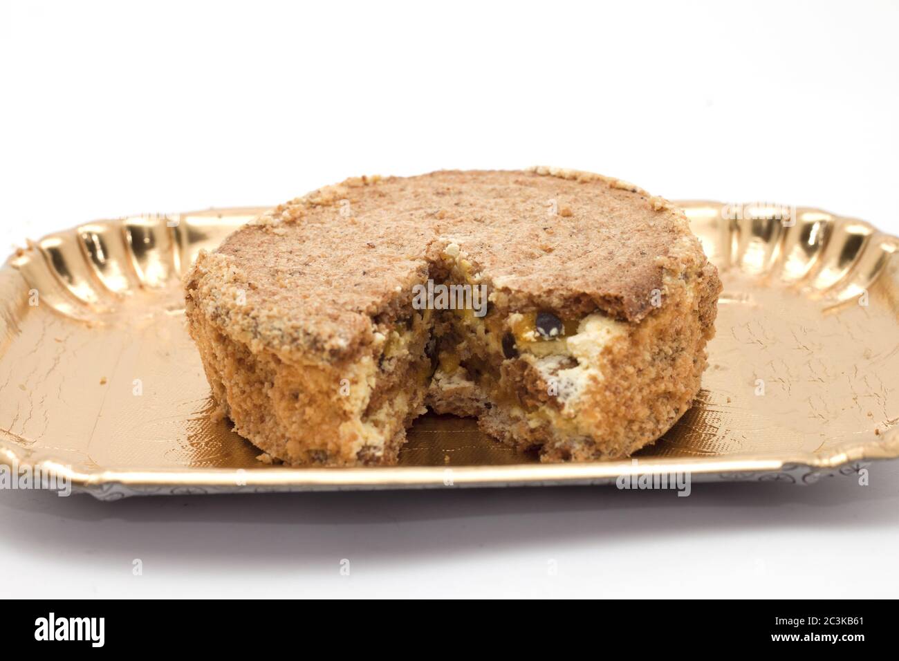 Delicious small round cake on a golden plate isolated on a white ...