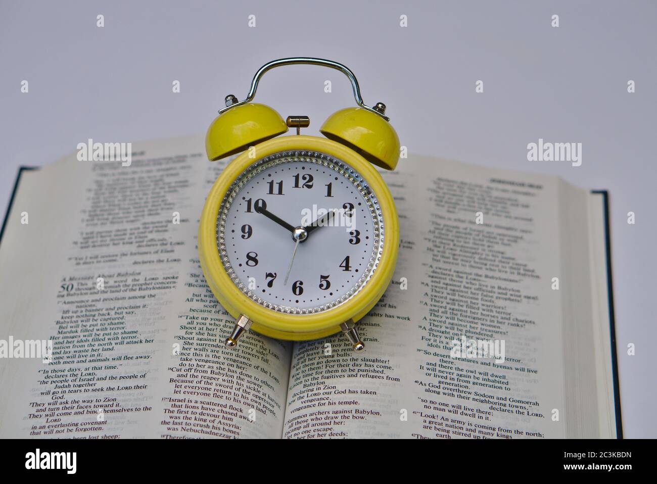 Yellow alarm clock on the open Bible on a white surface Stock Photo - Alamy