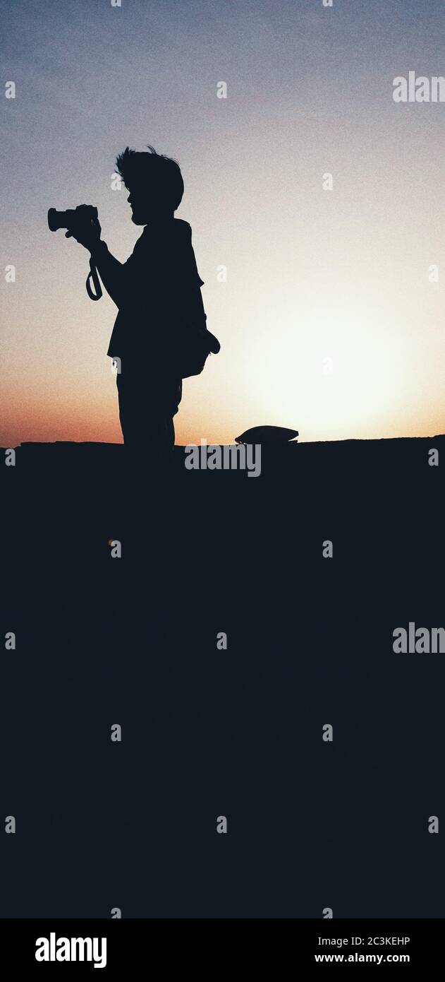 Vertical silhouette of an Asian photographer with camera in the nature ...