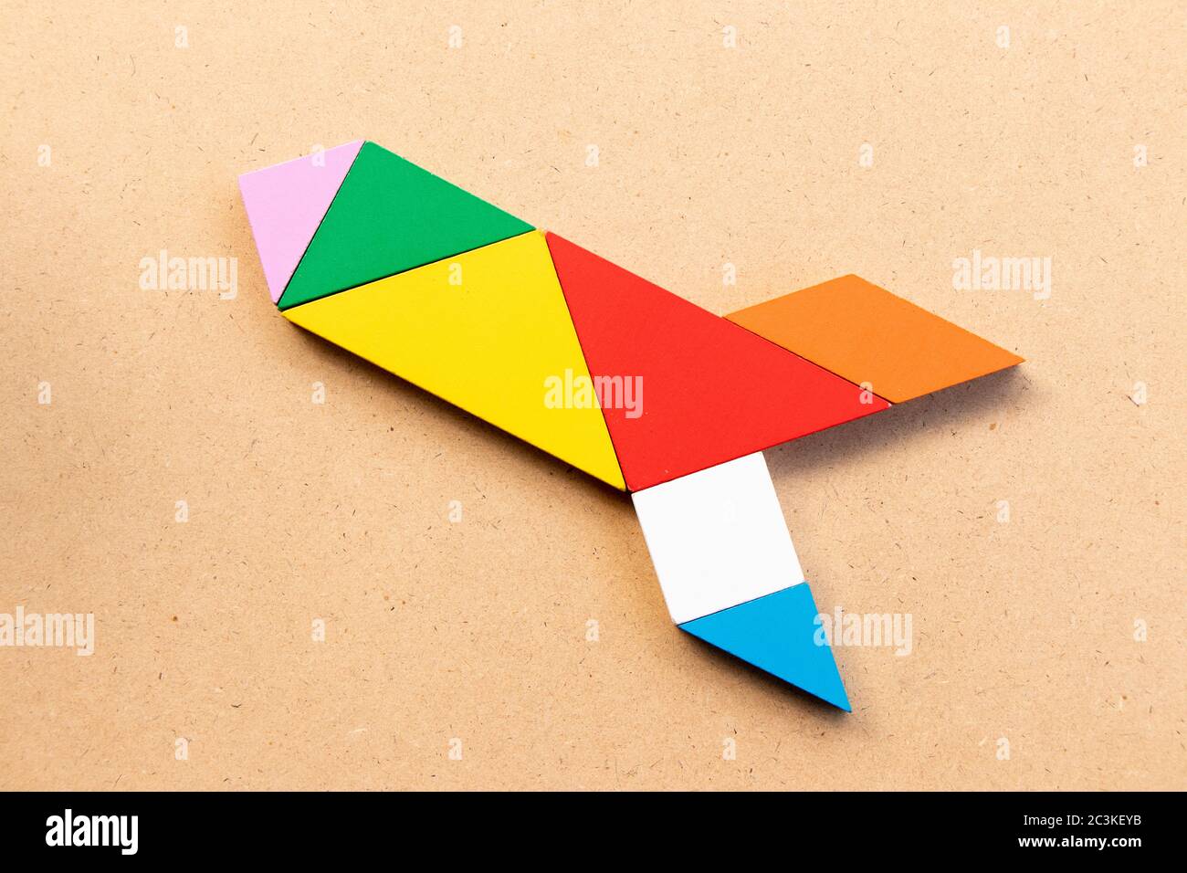 Color tangram puzzle in rocket or missile shape on wood bacground ...