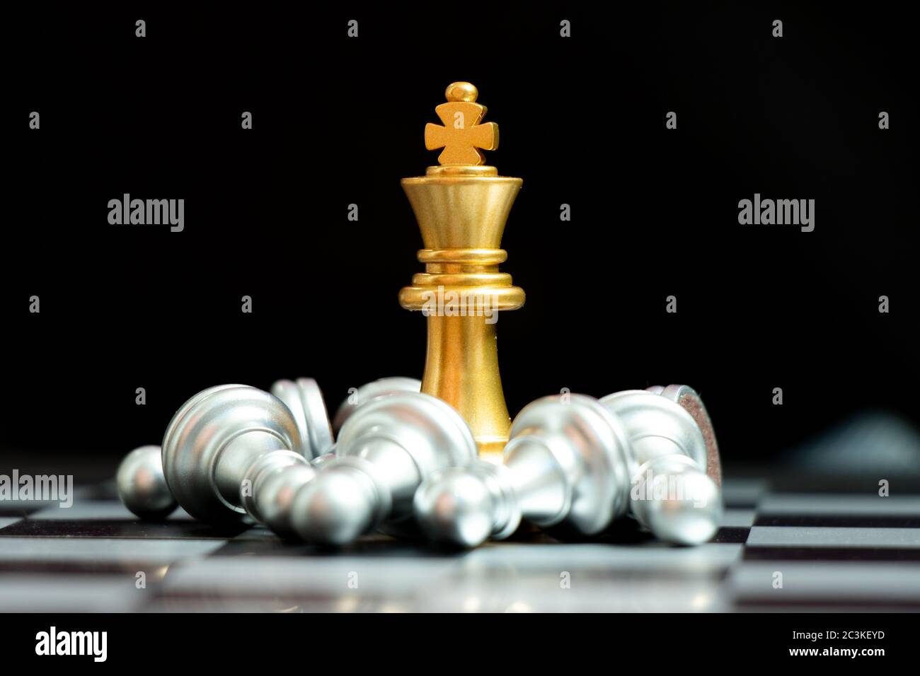 Gold king chess piece win over lying down pawn on black background ...