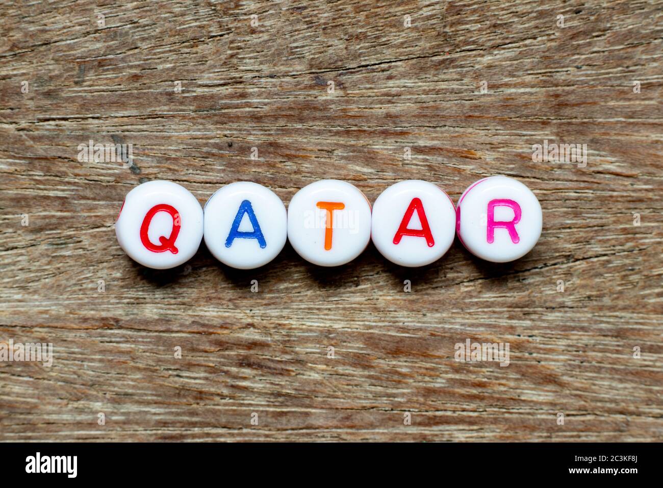 White bead with color letter in word qatar on wood background Stock ...