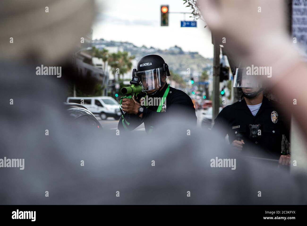 An LAPD officer aims a non-lethal weapon at protestors in Los Angeles ...