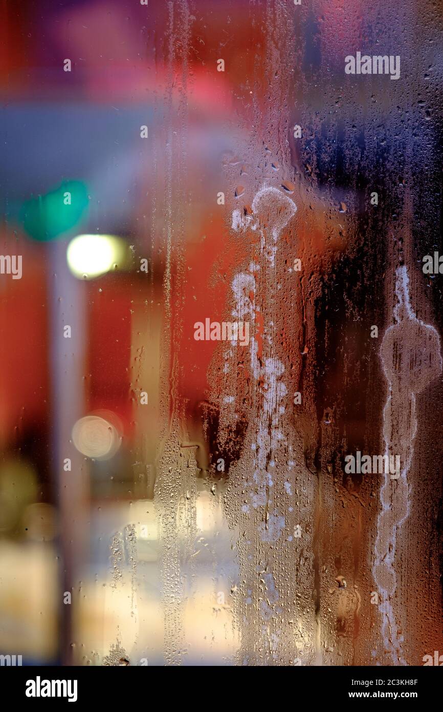 Vertical shot of the blurry colorful lights captured through a wet ...