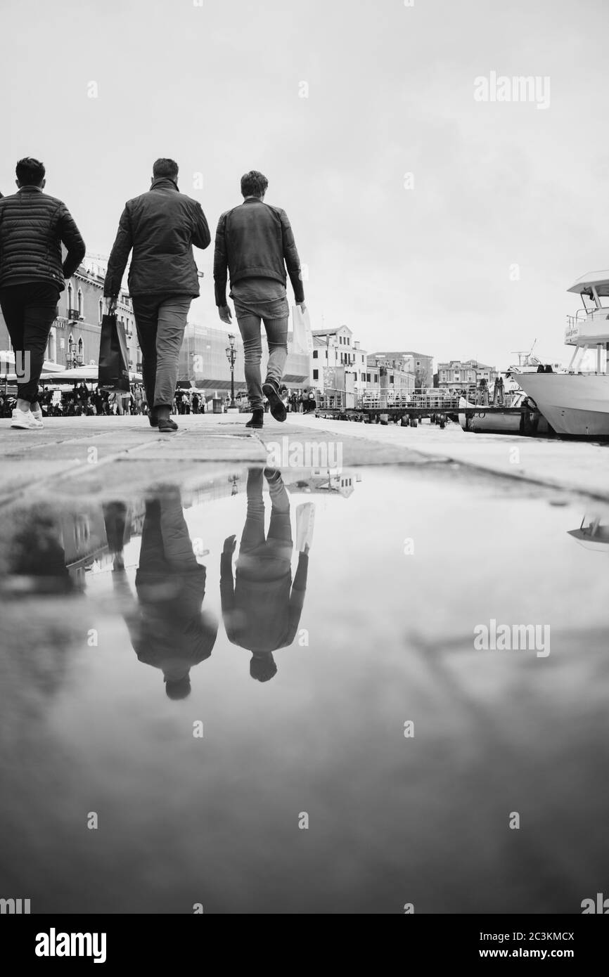 Vertical grayscale picture of human reflection on the water in the city ...