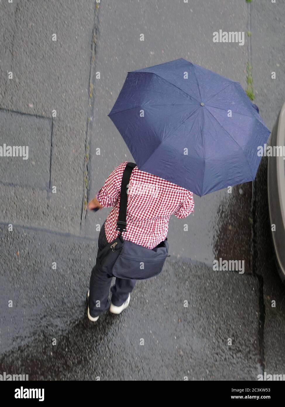 Vertical high angle shot of a person holding a blue umbrella over their ...