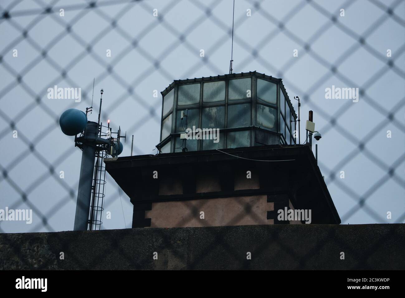 Telecommunications tower behind the blurry grid fence Stock Photo - Alamy