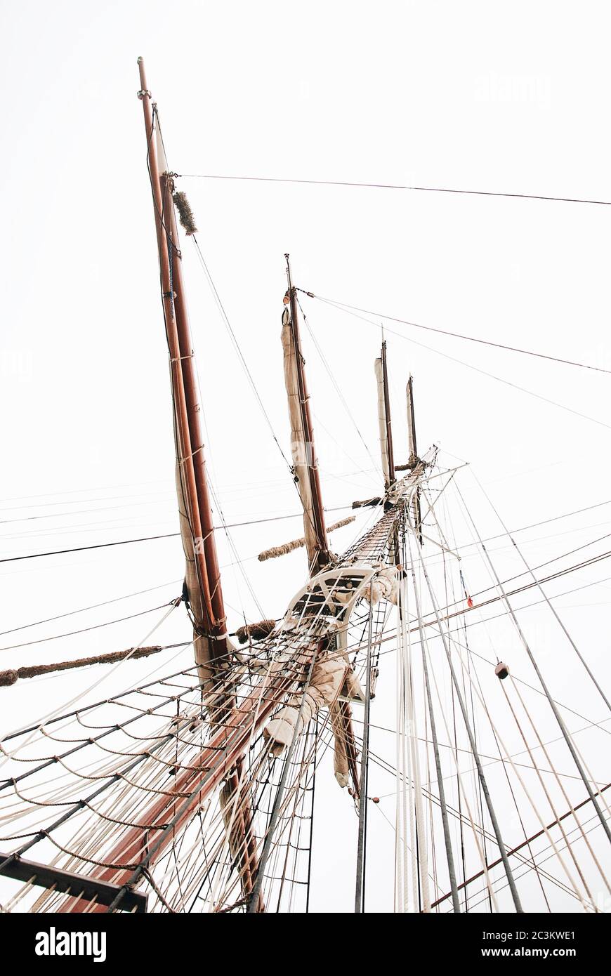 Vertical low angle shot of the masts of a ship with a white background ...