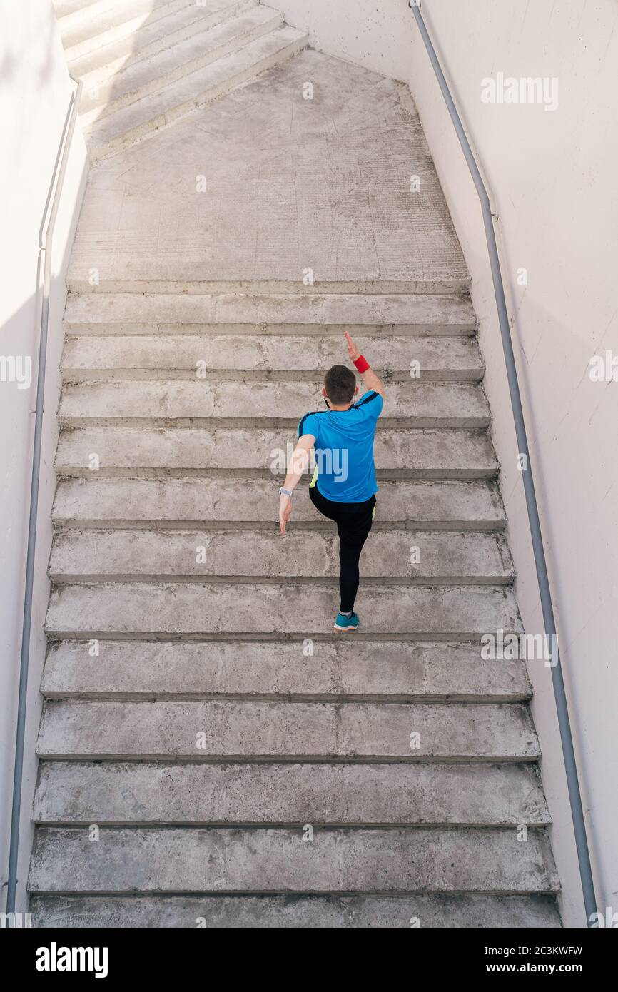 Young man running upstairs on city stairs. Fitness, sport, people ...