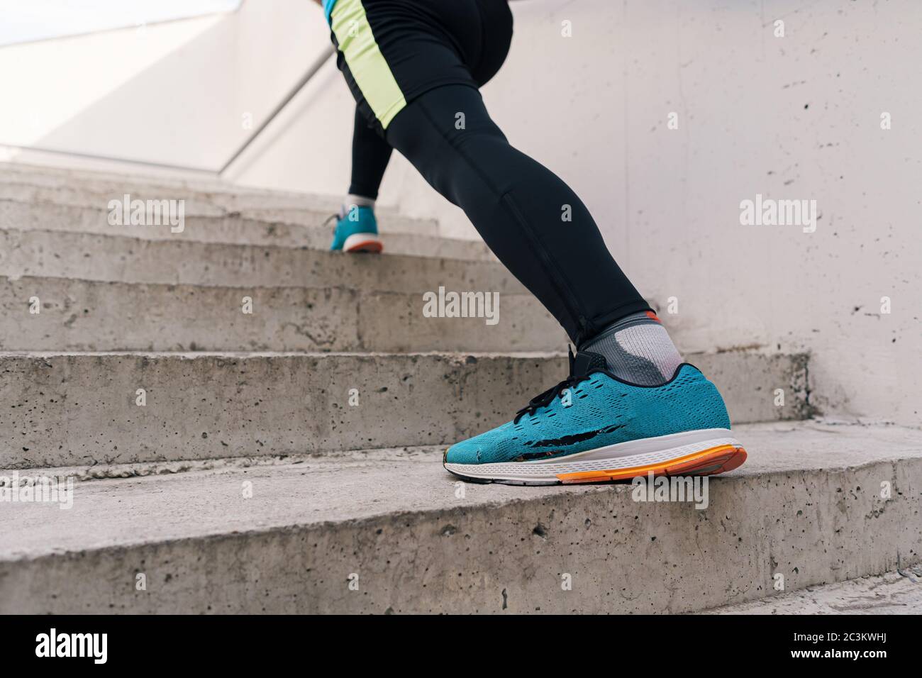 Young man runner getting ready to run stretching legs warm up quad ...