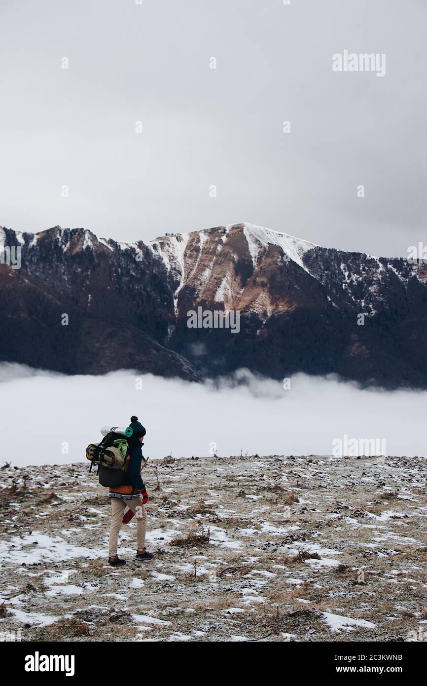Vertical shot of a person walking in the hills with hiking equipment ...