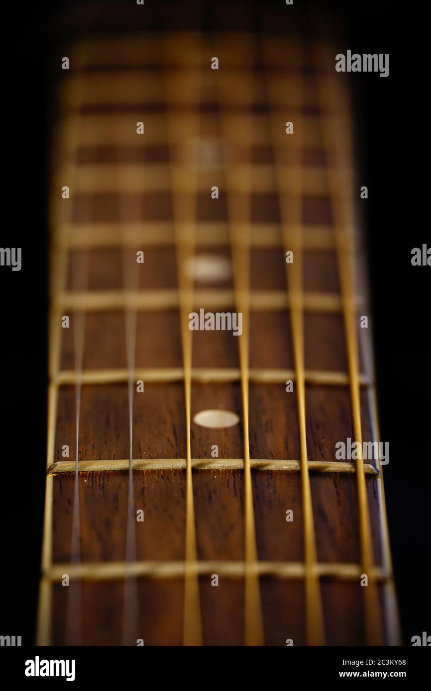 Vertical selective focus shot of strings and fretboard of acoustic ...