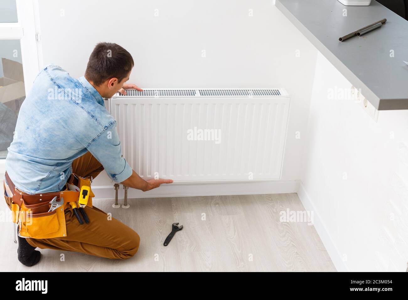 Man is repairing radiator battery in the room. Maintenance repair works ...
